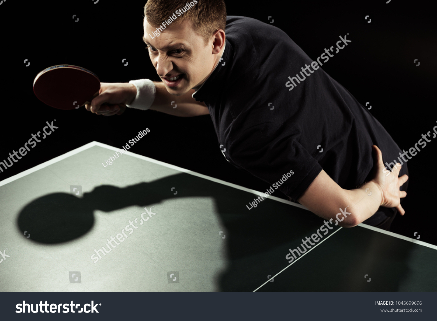 angry tennis player in uniform playing table tennis isolated on black_站 ...