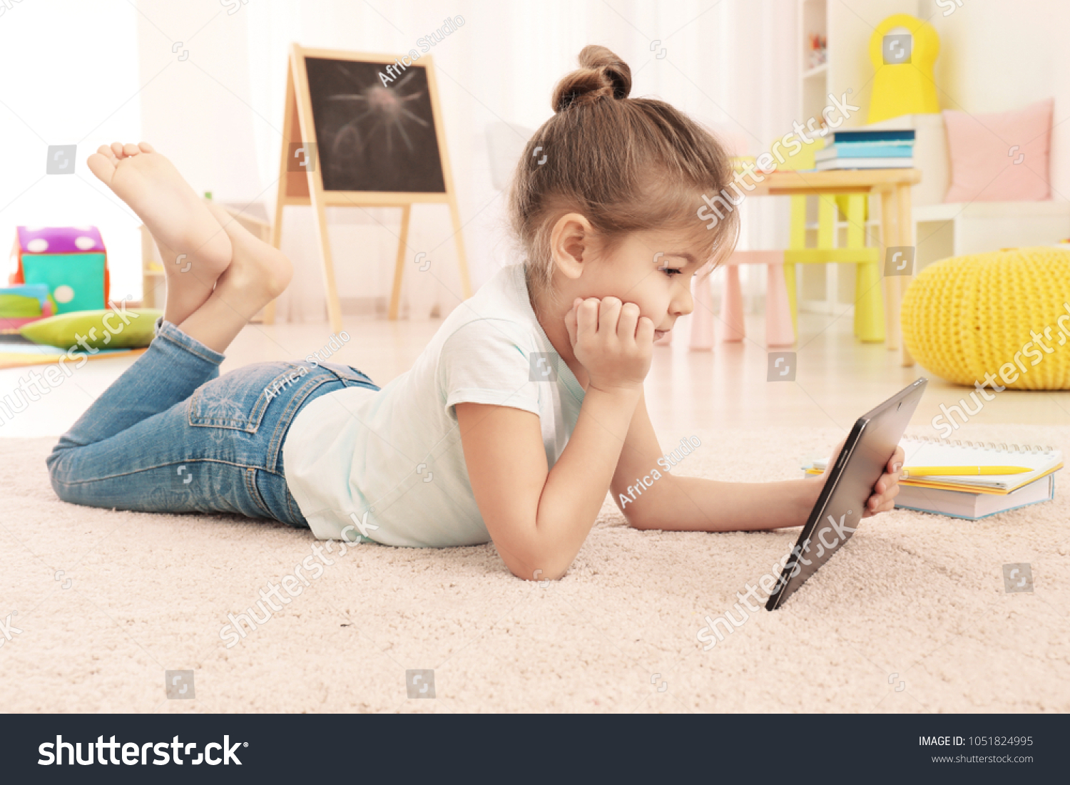 Cute little girl using tablet PC while doing homework indoors_站酷海洛_正版图片 ...