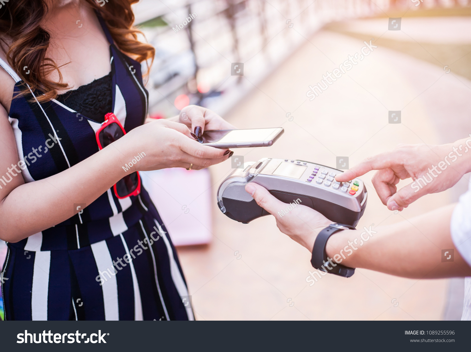 A woman's hand holding and using of smart phone to pay for goods to a ...