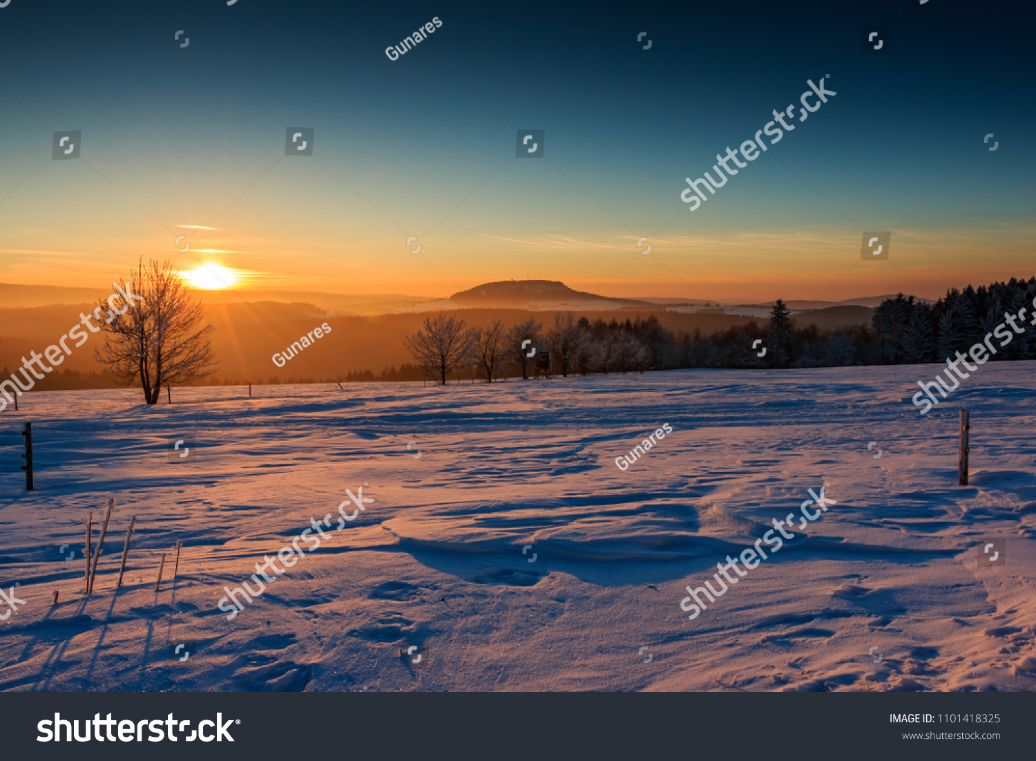 Sunset in the golden sunlight over the winterly Ore Mountains. View to ...