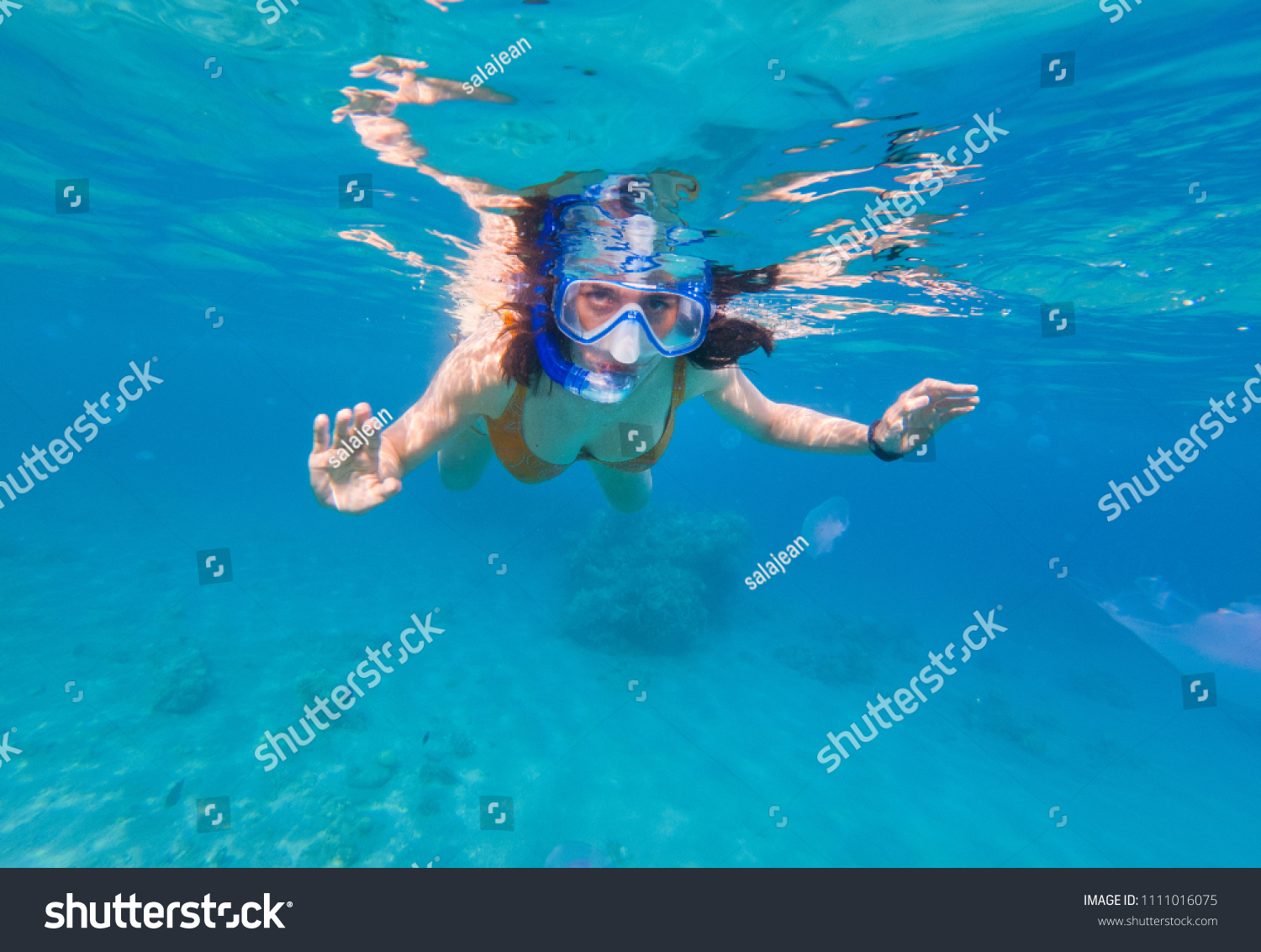 Underwater shot of a young woman snorkeling in tropical sea above coral ...