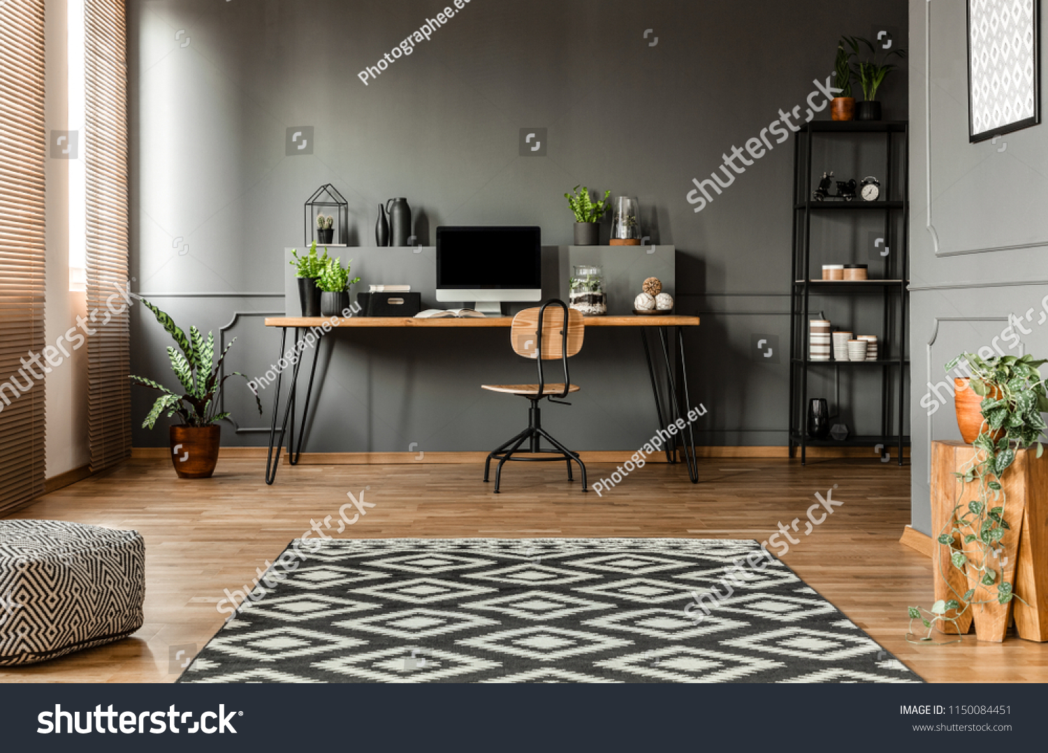 Patterned carpet and pouf in simple grey workspace interior with ...