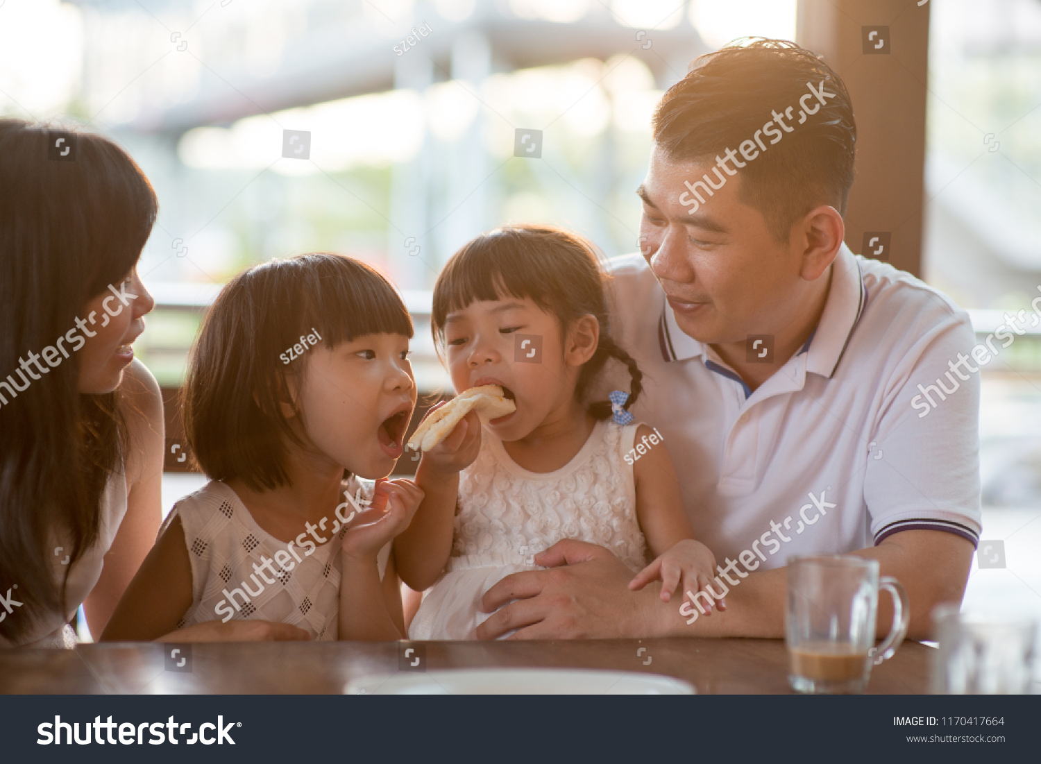 Children eating and sharing butter toast at cafe. Asian family outdoor lifestyle with natural ...