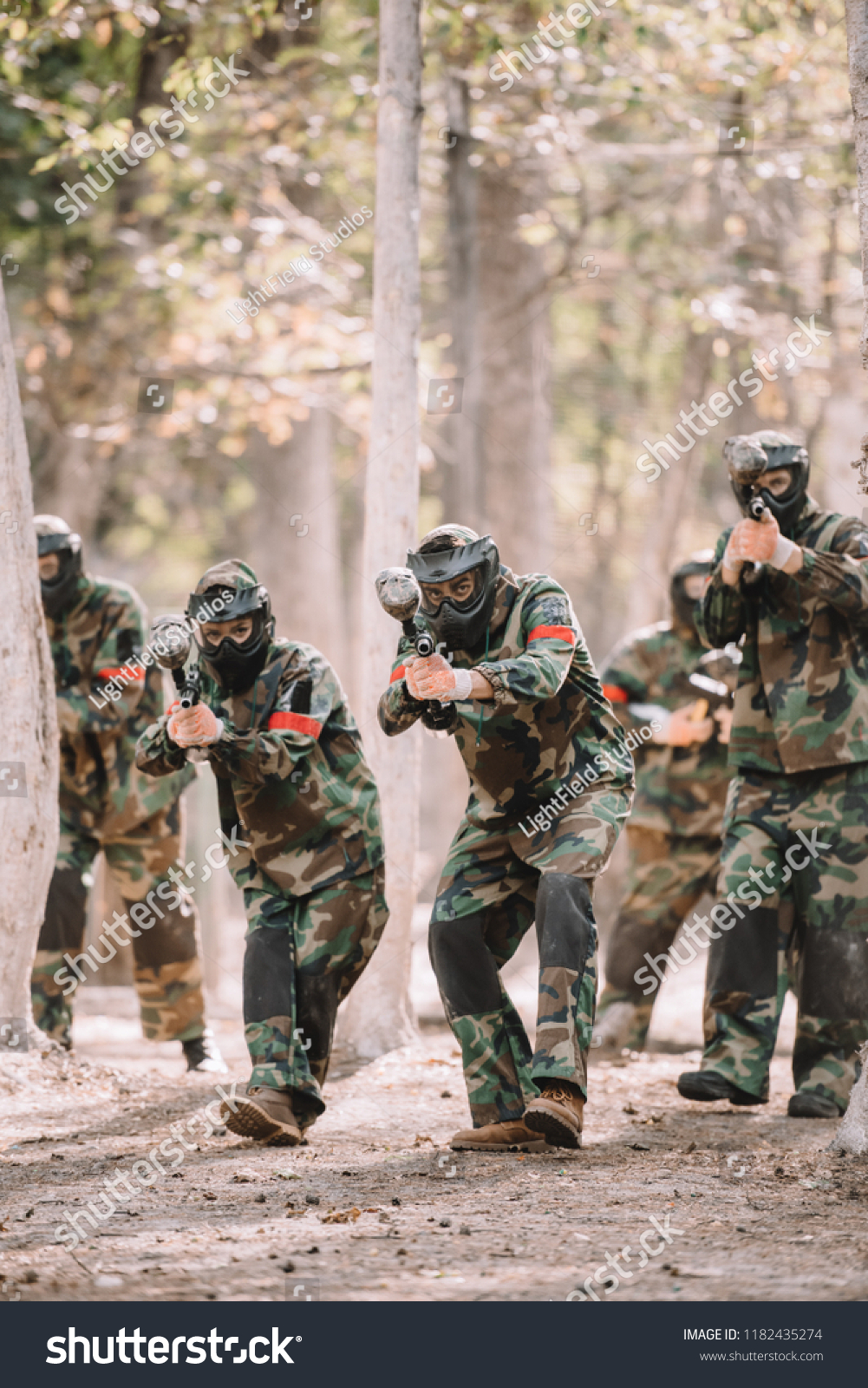 paintball team in uniform and protective masks running and aiming by paintball guns outdoors_站酷海 ...