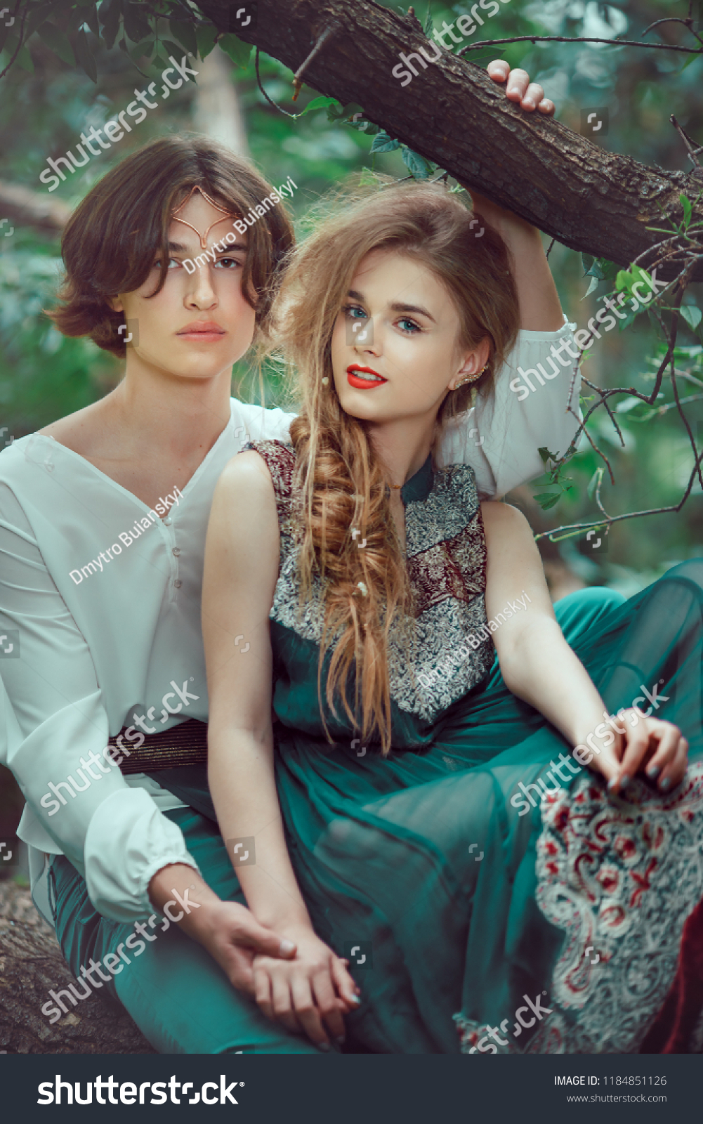 Young couple of elves in love siting on branch in magical forest ...