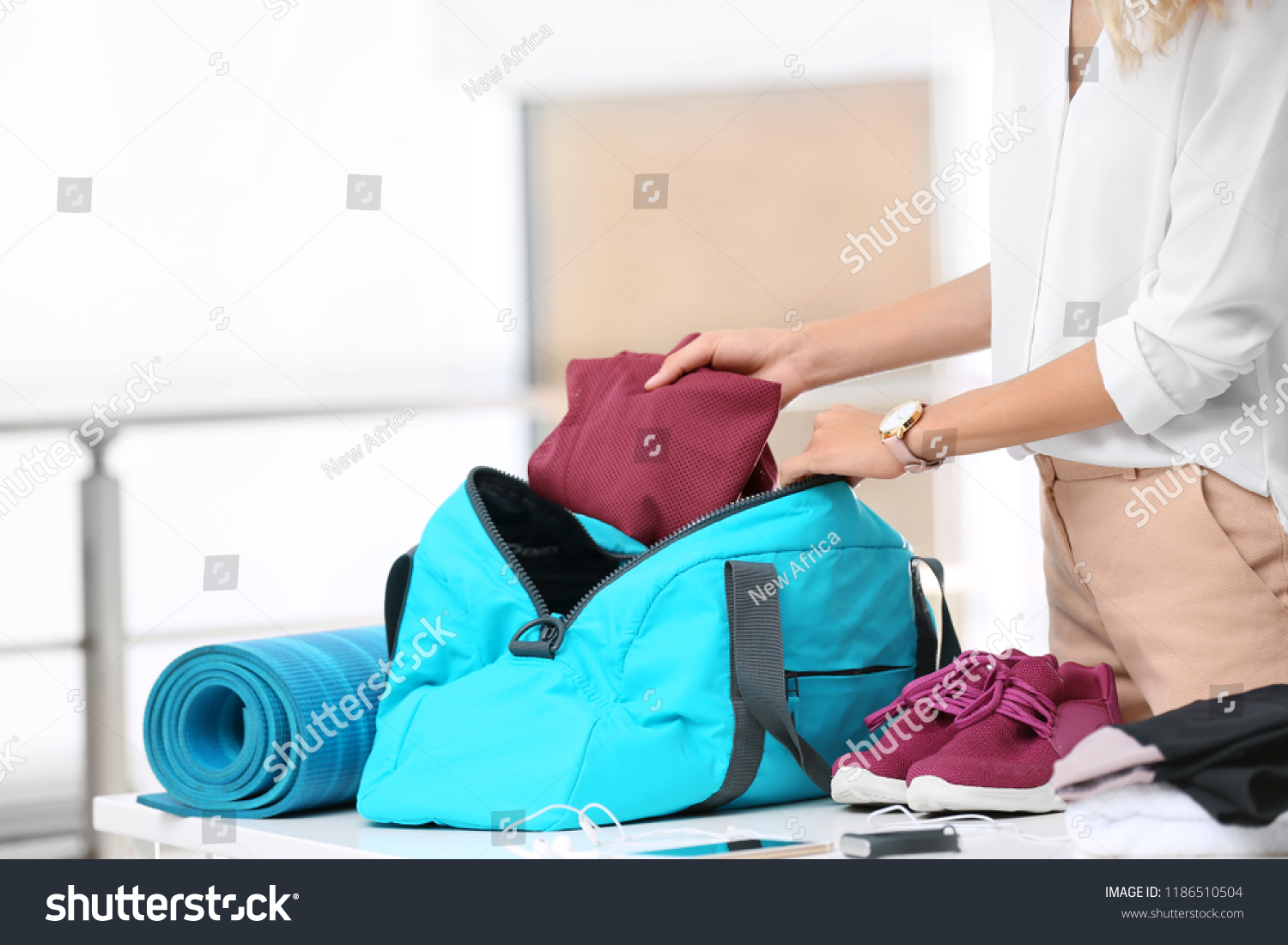 Young businesswoman packing sports stuff for training into bag in ...