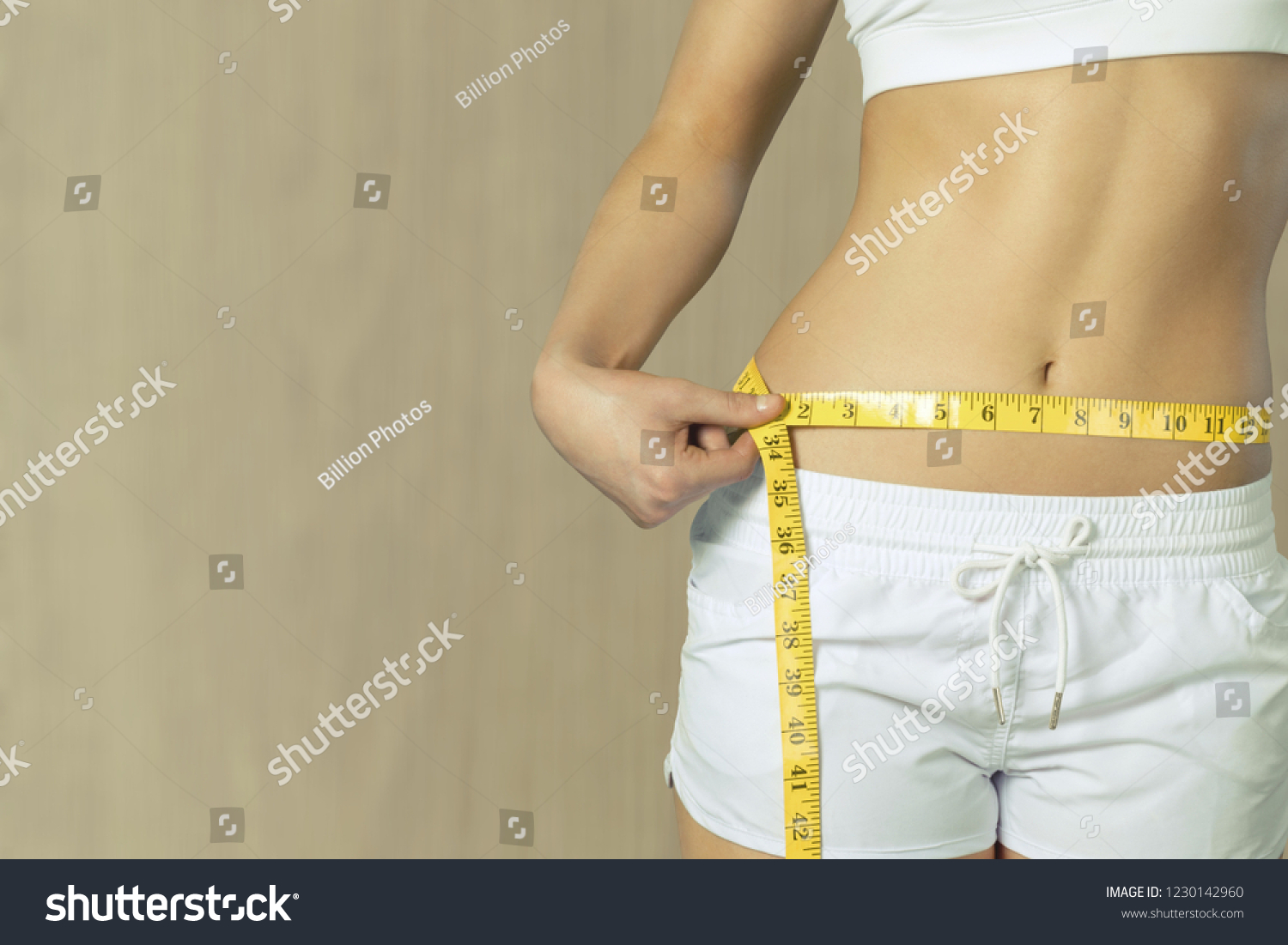 Slim young woman measuring her thin waist with a tape measure close up ...