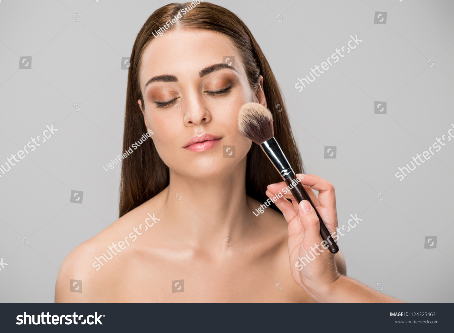 beautiful young woman applying face powder with cosmetic brush isolated ...