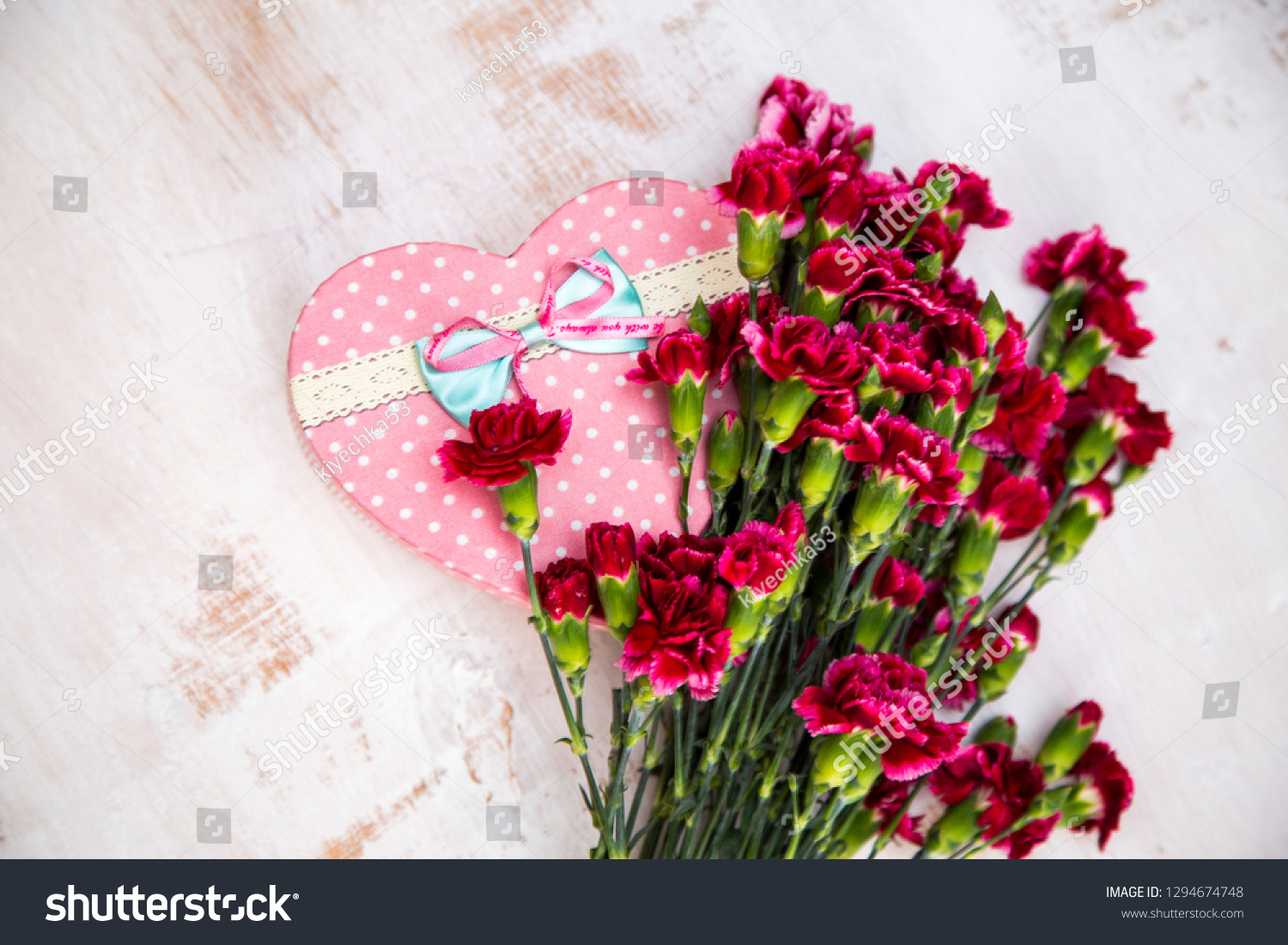 heart-shaped gift box with burgundy carnations lie on a light worn ...