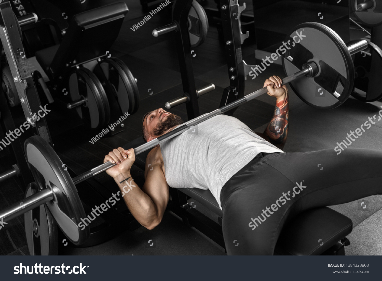 Bearded man bodybuilder exercising at gym lying doing bench press ...
