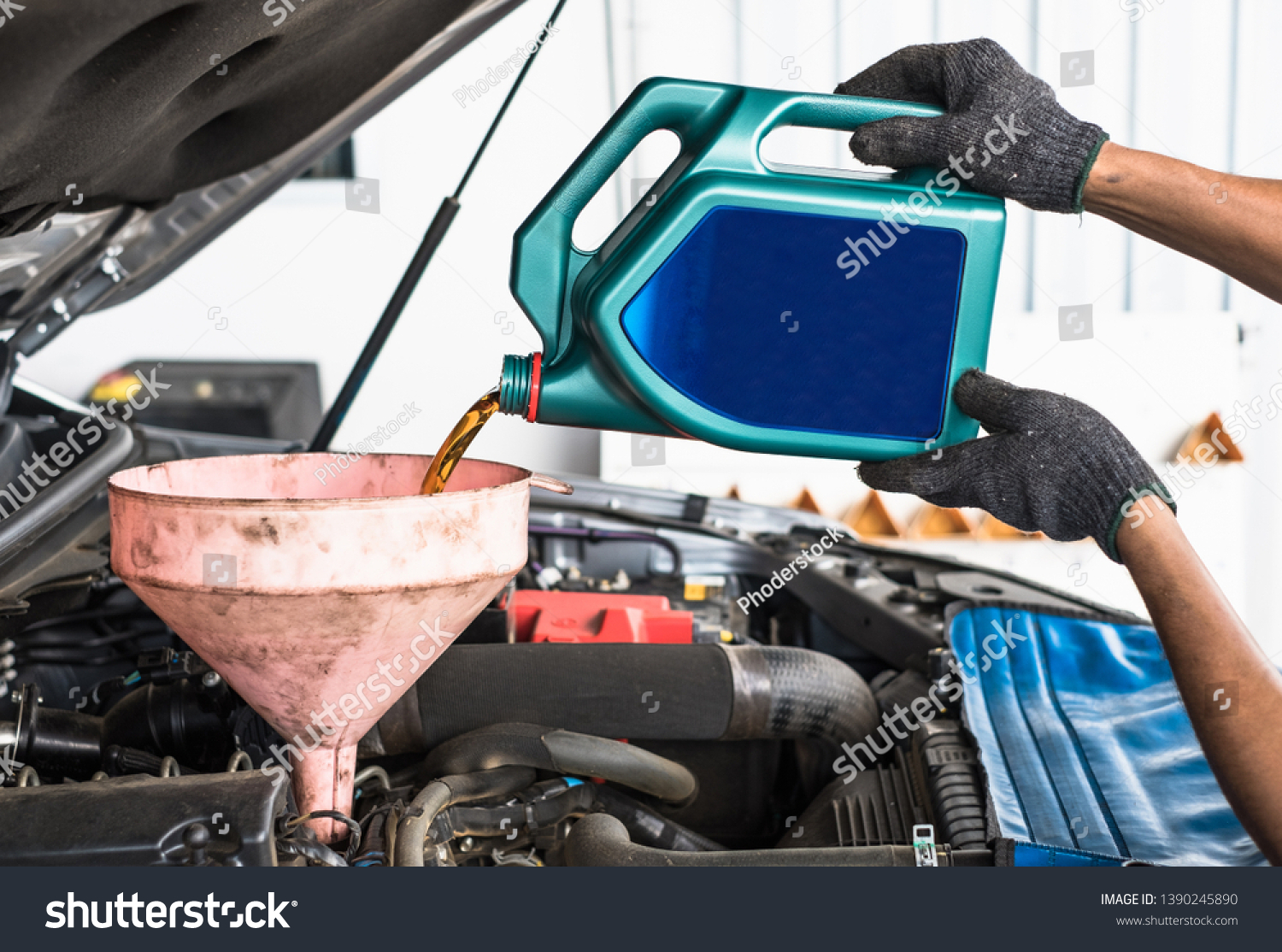 Close up of car mechanic hand filling new oil into engine at repair ...