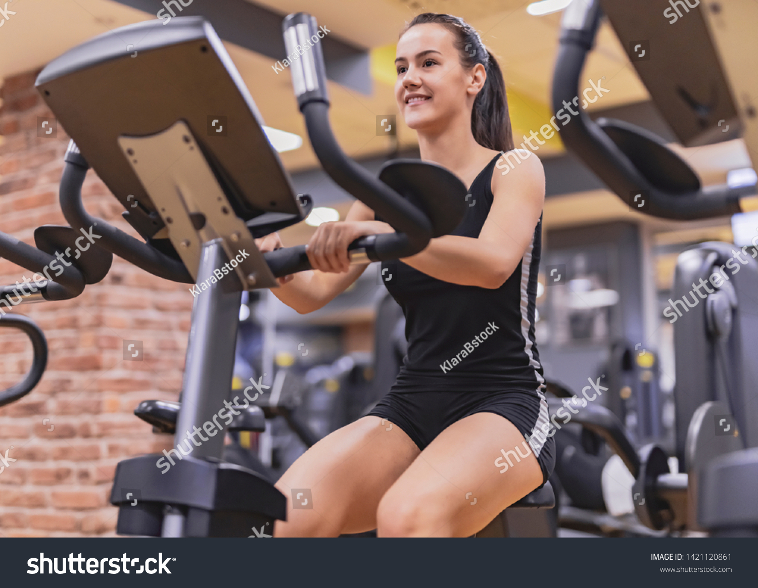 Happy female doing indoor biking in a fitness club. Selective focus. Motion Blur. Focus on ...