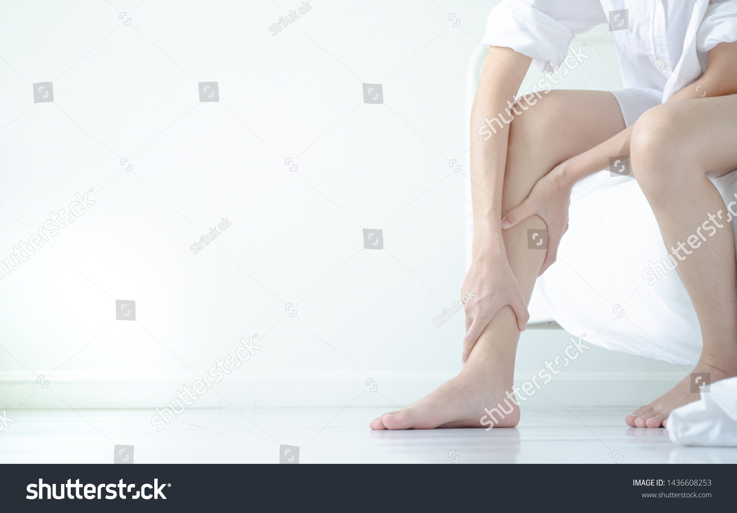 Asian girl wearing white dress have leg pain. The woman was squeezing ...
