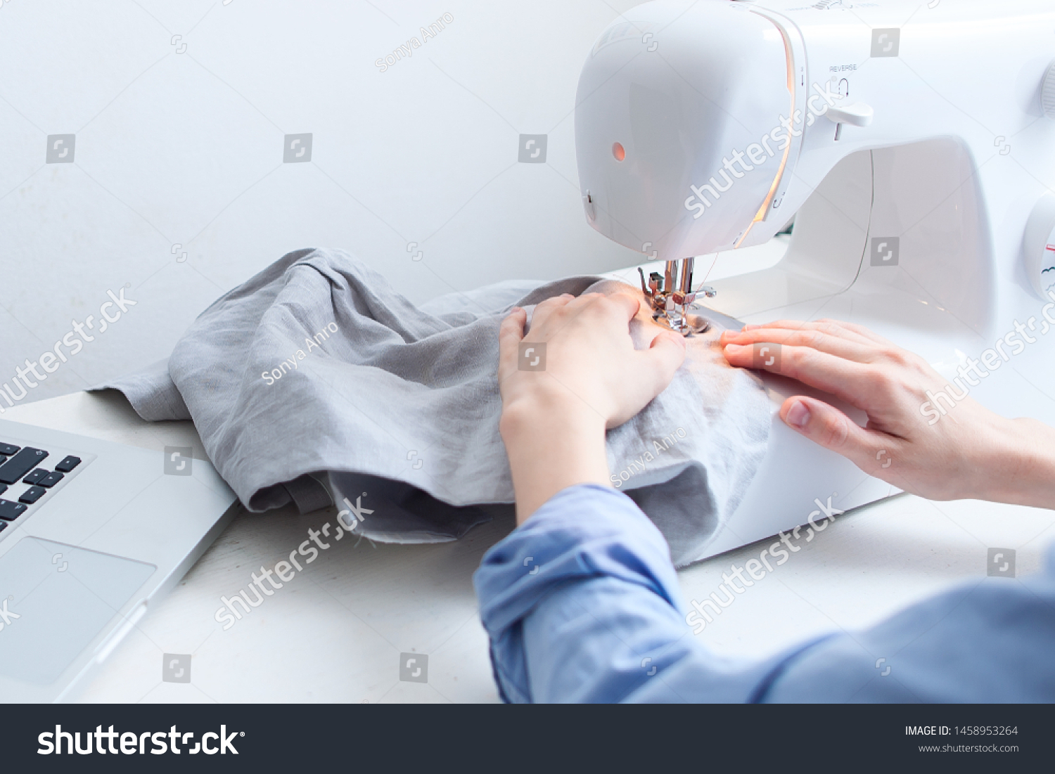 Closeup portrait of young woman seamstress sitting and sews on sewing ...