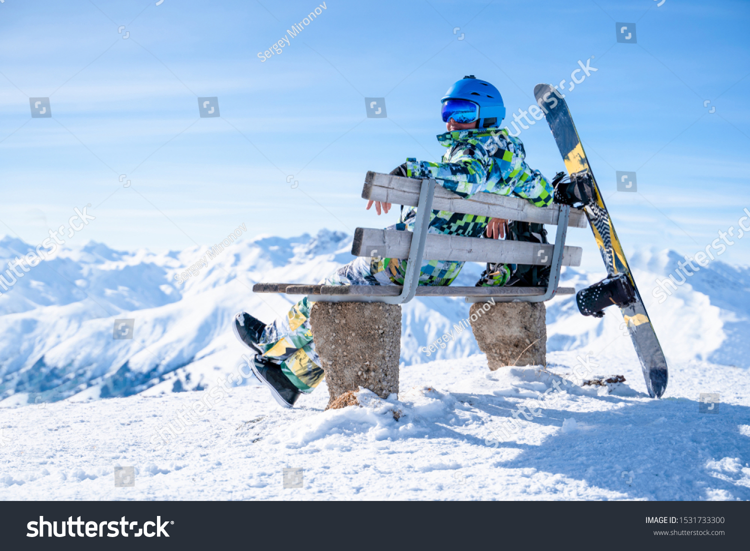 Photo of athlete sitting on bench with snowboard at winter resort._站酷海洛 ...