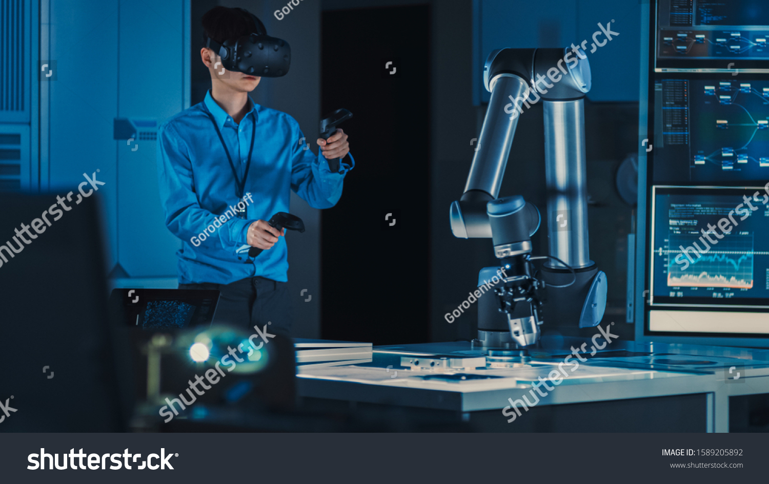 Professional Japanese Development Engineer in Blue Shirt is Controlling a Futuristic Robotic Arm ...
