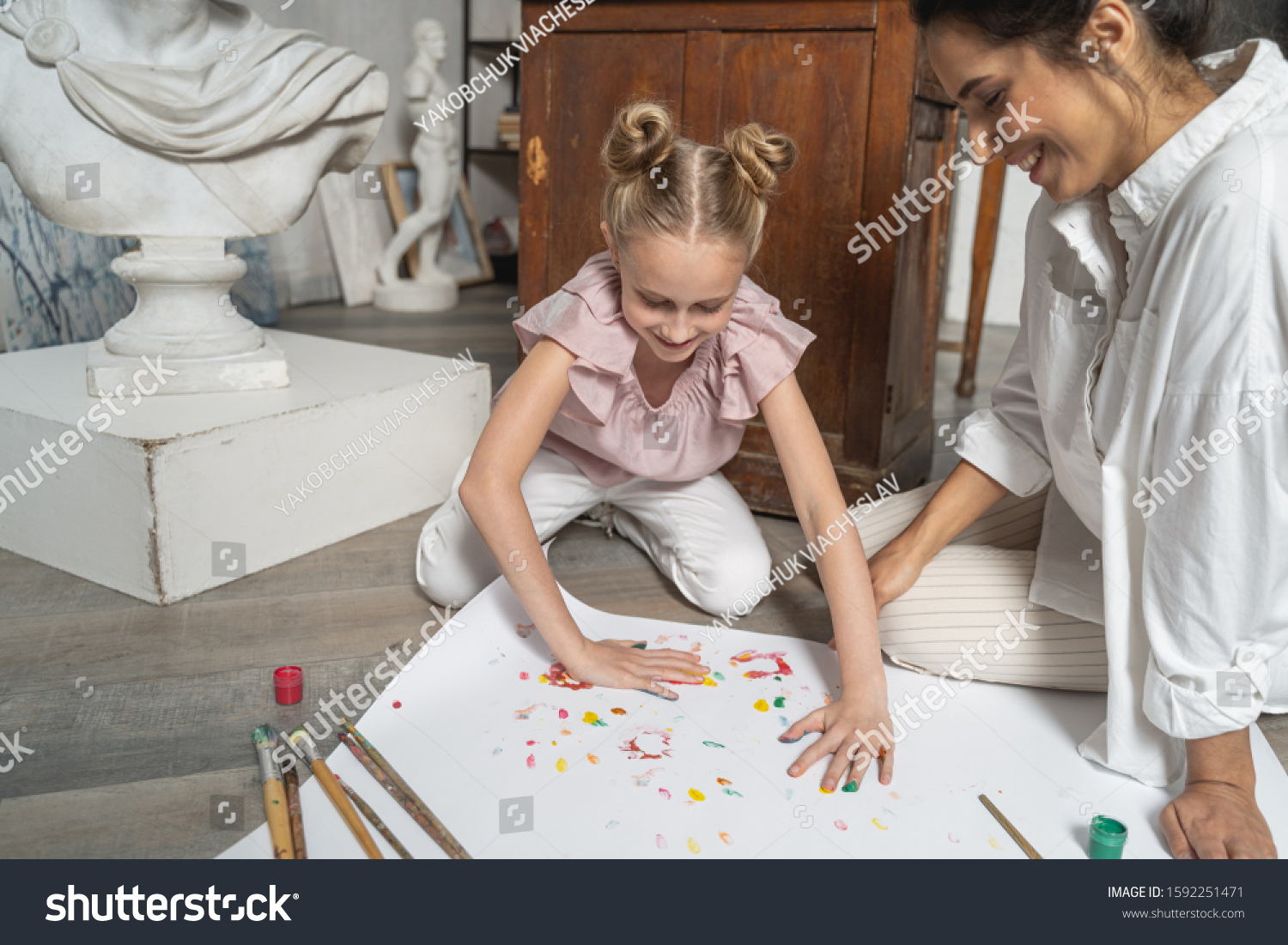 Caucasian happy kid having great time with her pretty mummy in art room ...