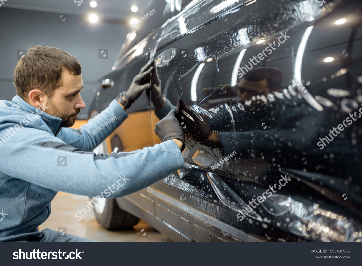 Car service worker sticking anti-gravel film on a car body with ...
