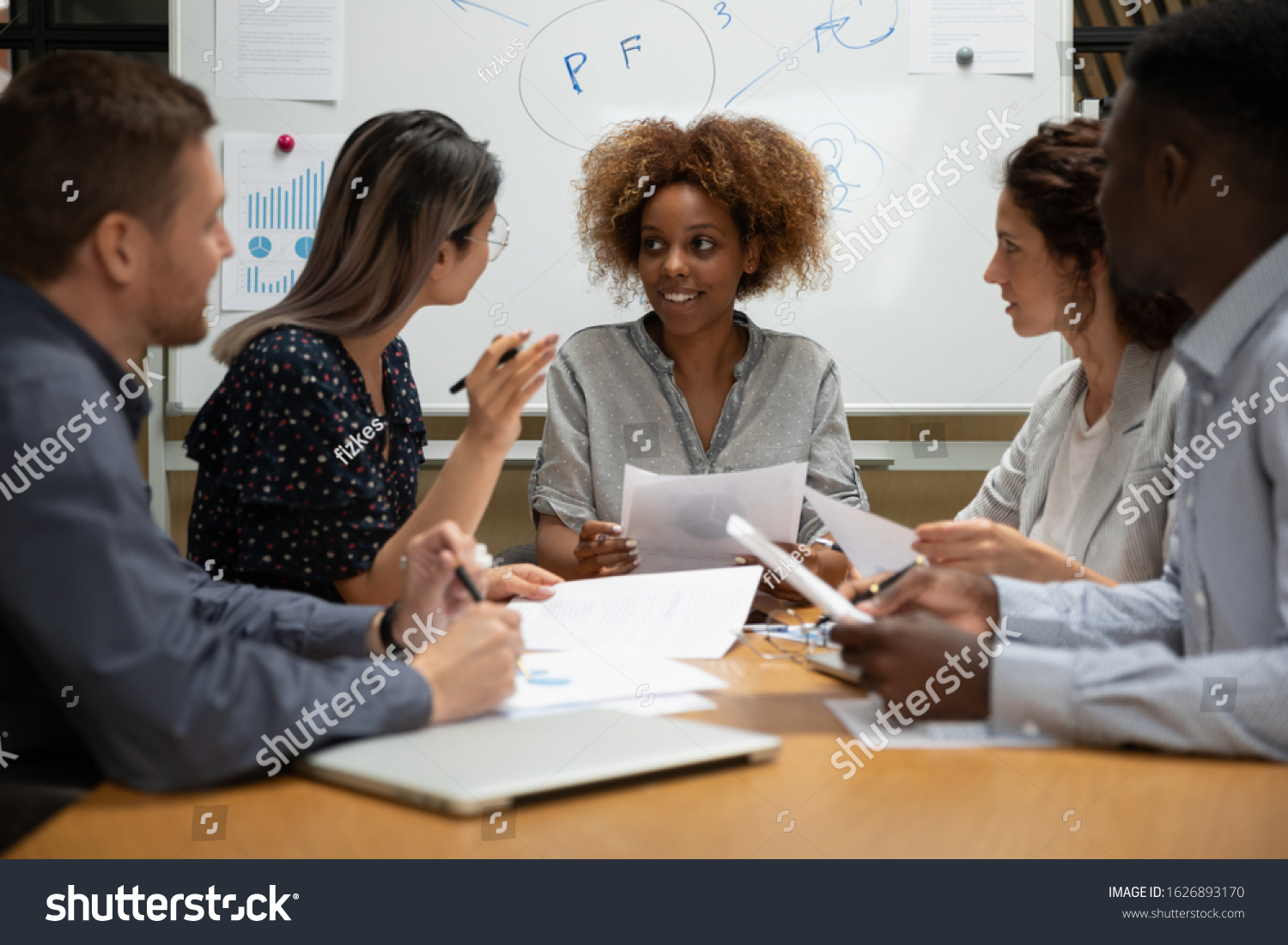 Diverse multiracial work team sit at office desk brainstorm discussing ...