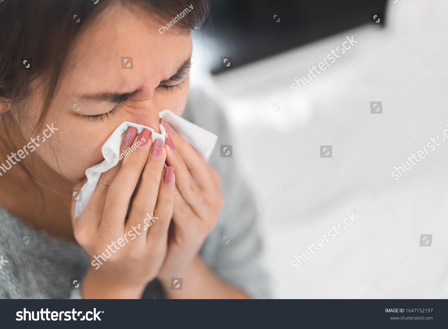 Sick asian woman have hight fever flu and sneezing into tissue on bed in bedroom Medical and ...