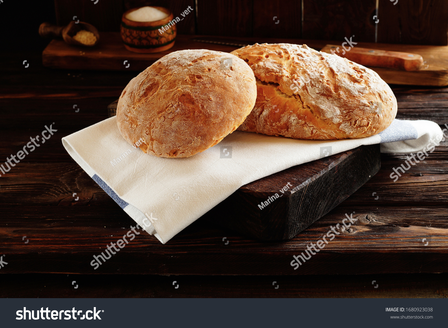 Two loaves of wheat bread made at home lie on a white linen napkin and ...