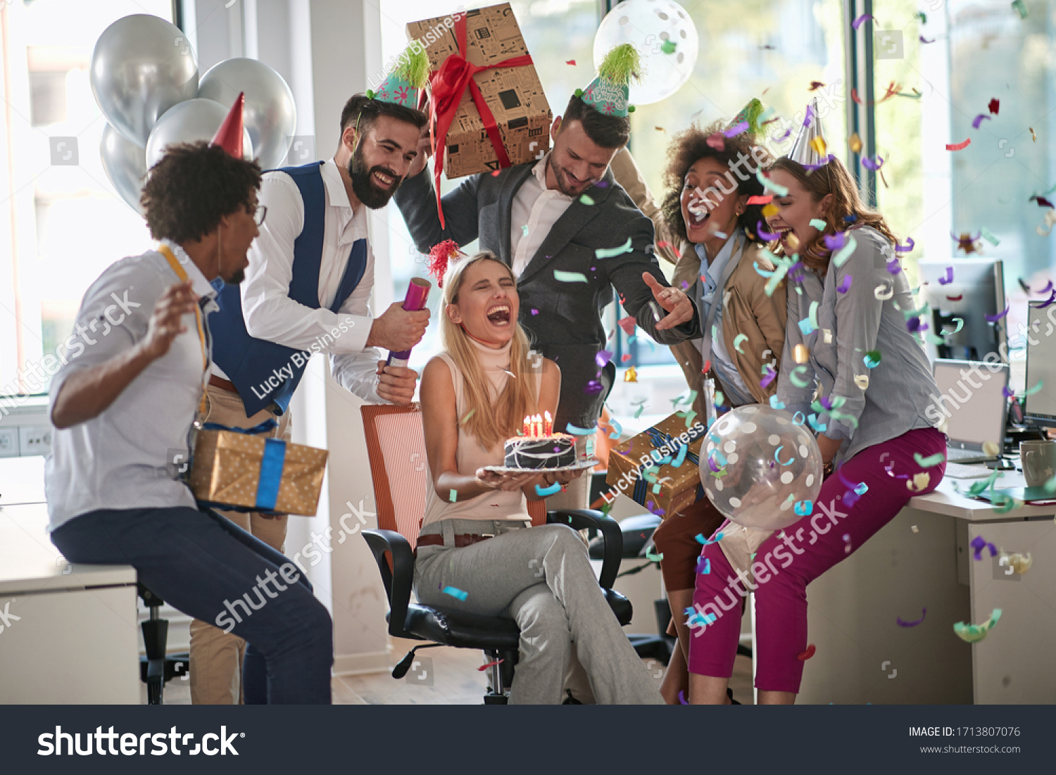 coworkers surprising female colleague with birthday cake at work in ...