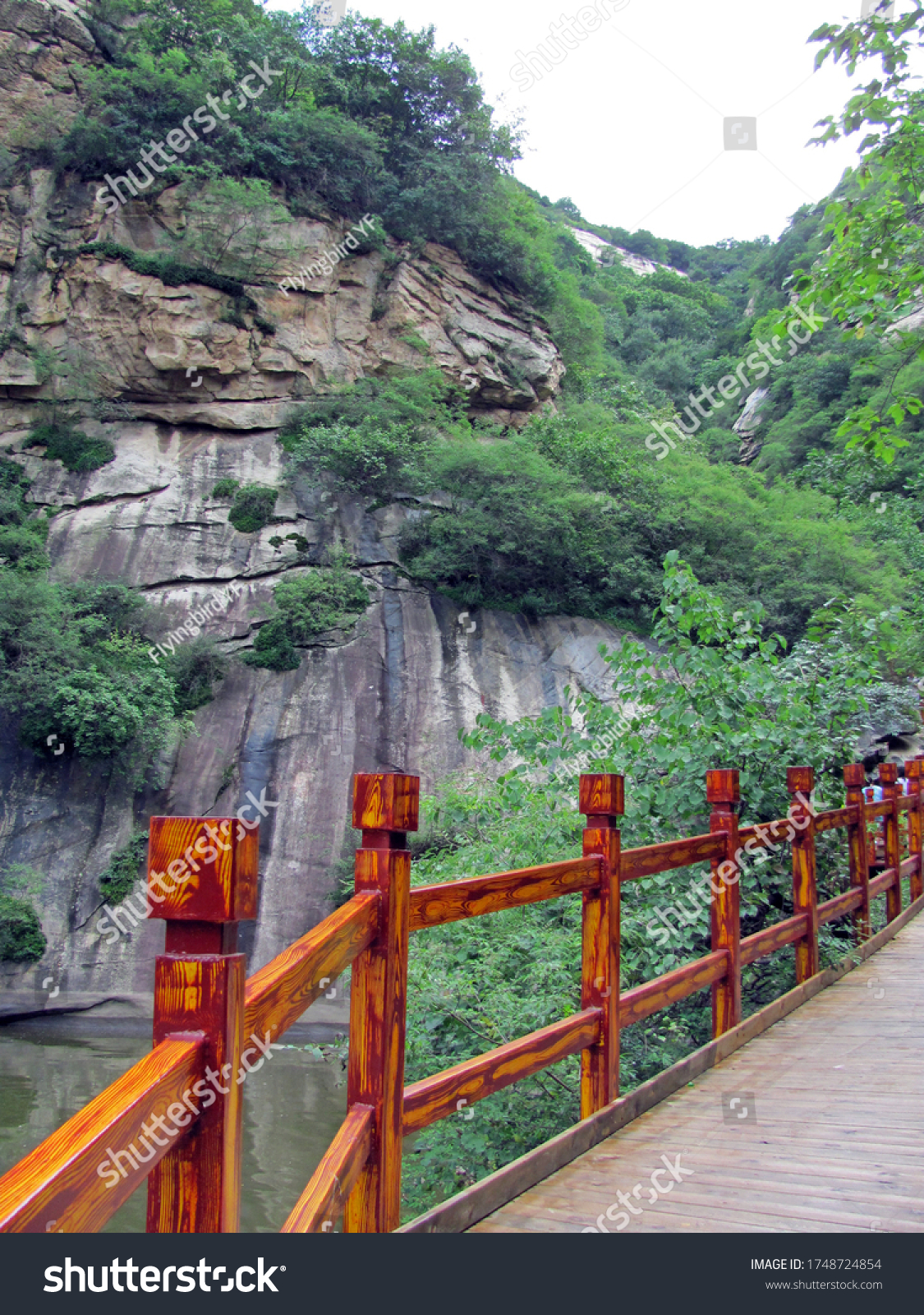 Wooden boardwalk with wood-like metal railings over stream in mountain ...