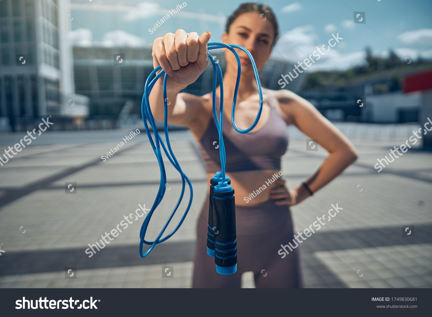 Slim dark-haired lady in leggings and a top clutching her jump rope in ...