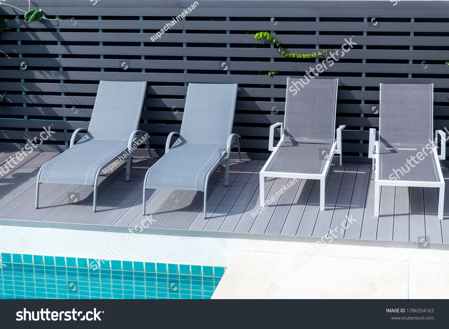 A row of launch chairs by swimming pool. Poolside sitting area for ...