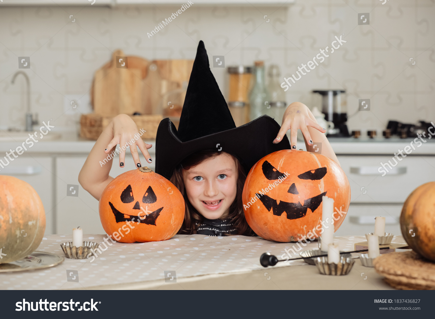 Happy halloween. Cute little girl in witch costume with carving pumpkin. Happy family preparing ...