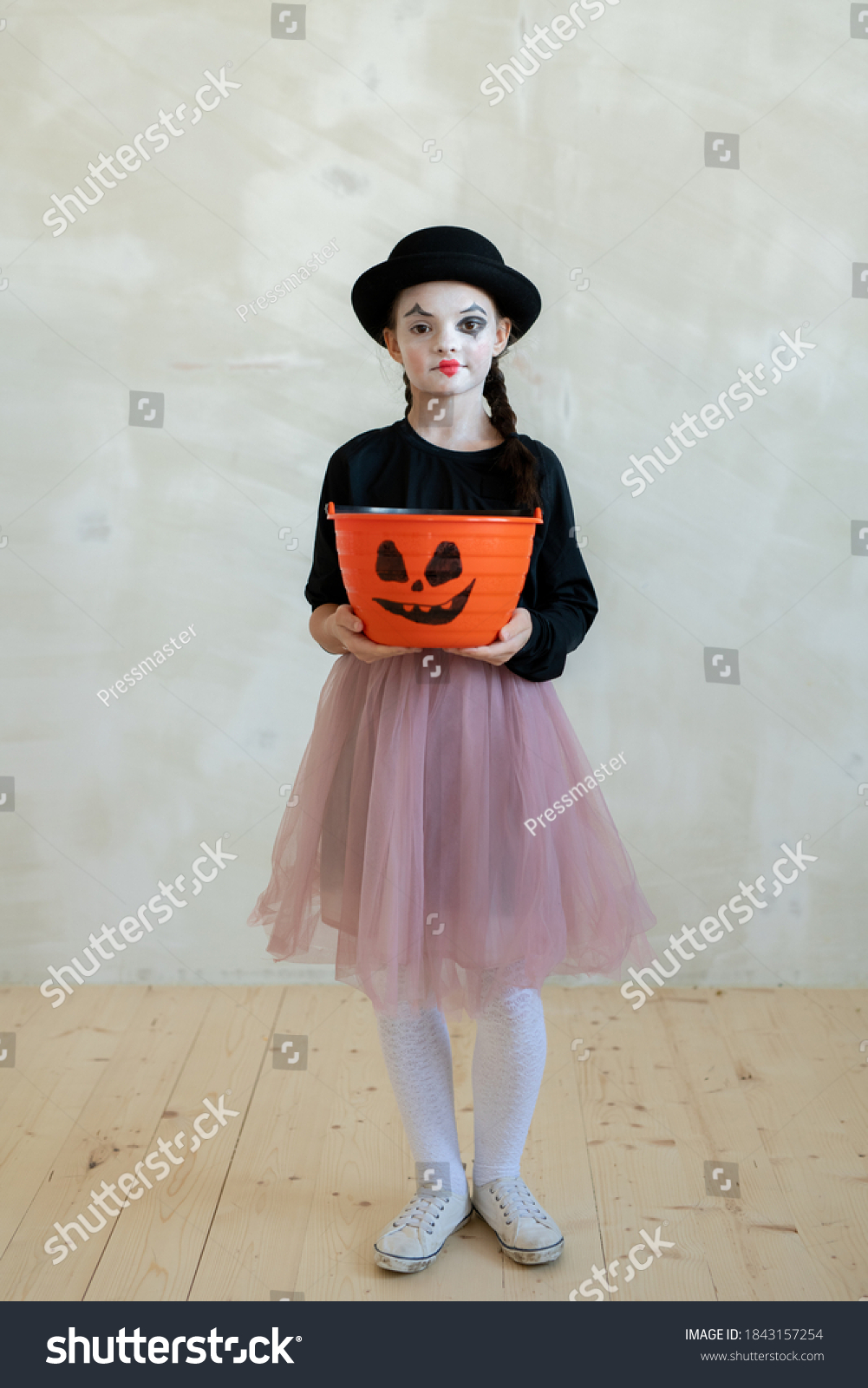 Portrait of content braided girl in tut skirt holding orange bucket for ...