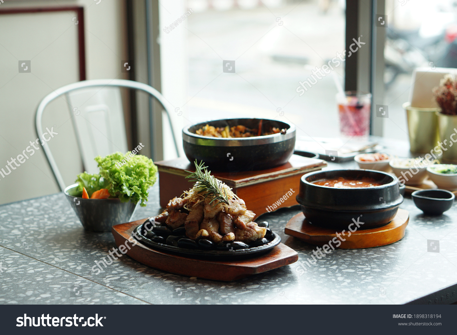 Korean food set on the table. Grilled pork belly served on hot stone ...