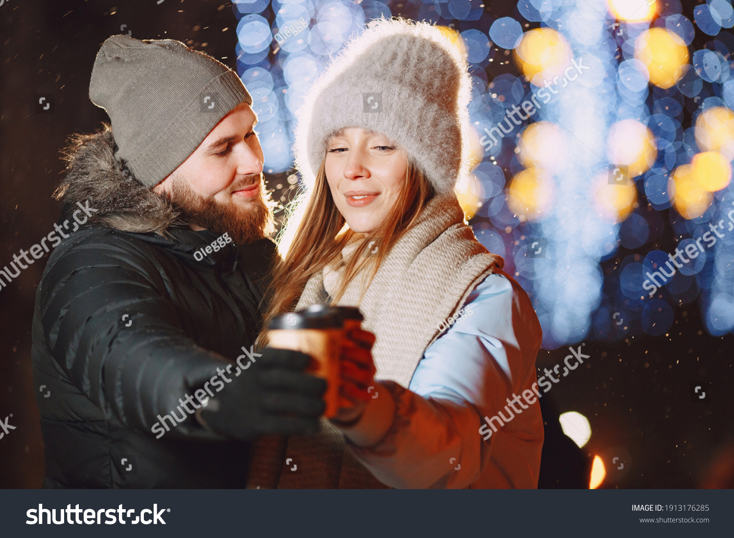 Winter holidays conception. Outdoor night portrait of young couple. Posing in street of European ...
