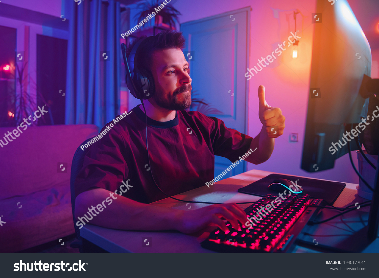 Young man plays computer games at home. Neon streamer studio. The guy ...