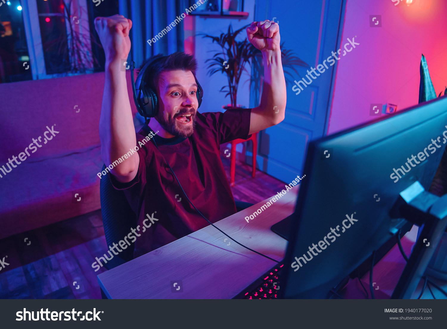 Young man plays computer games at home. Neon streamer studio. The guy ...