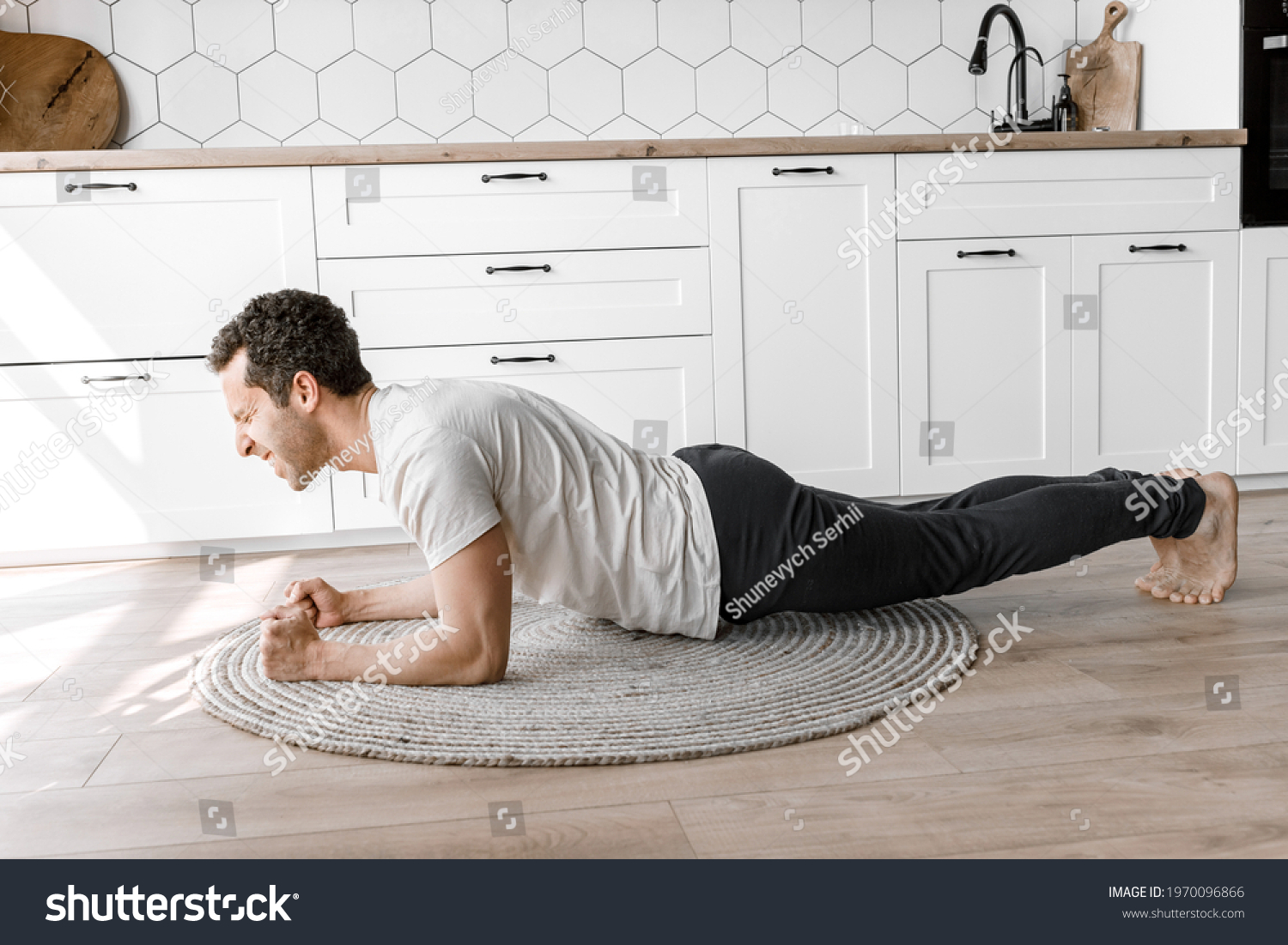 Home Workout. Sporty young man working hard and making plank exercise ...