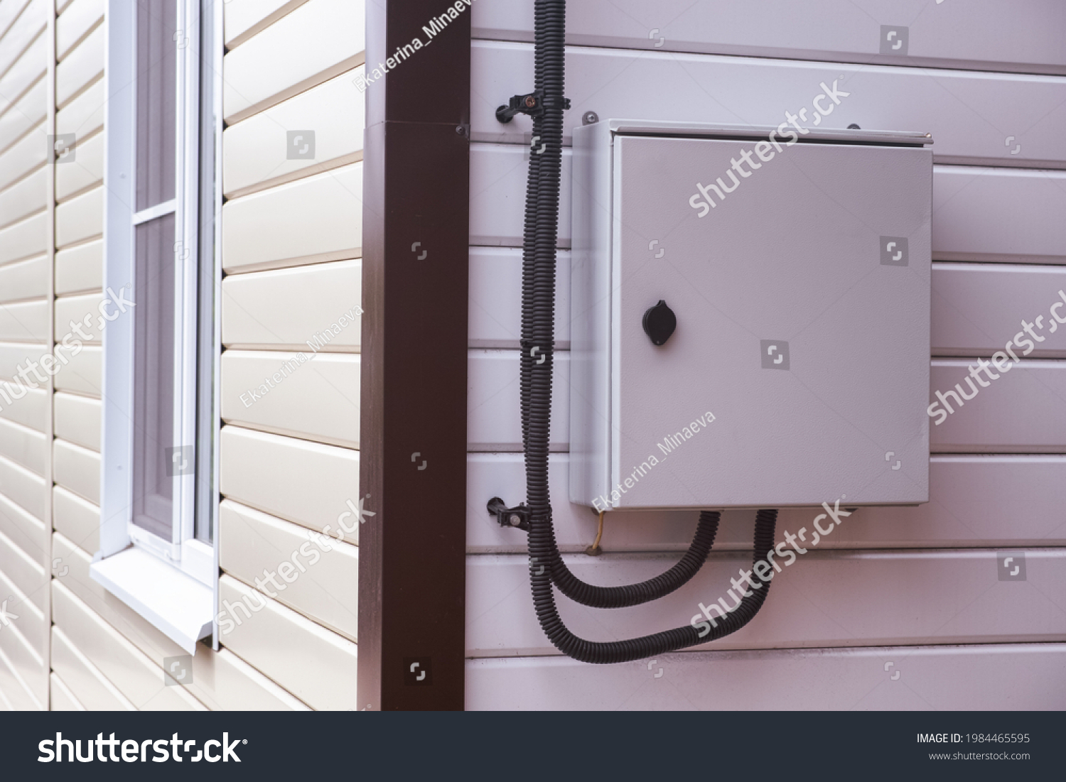 An electrical panel with electric wires in it on a wall outside the ...