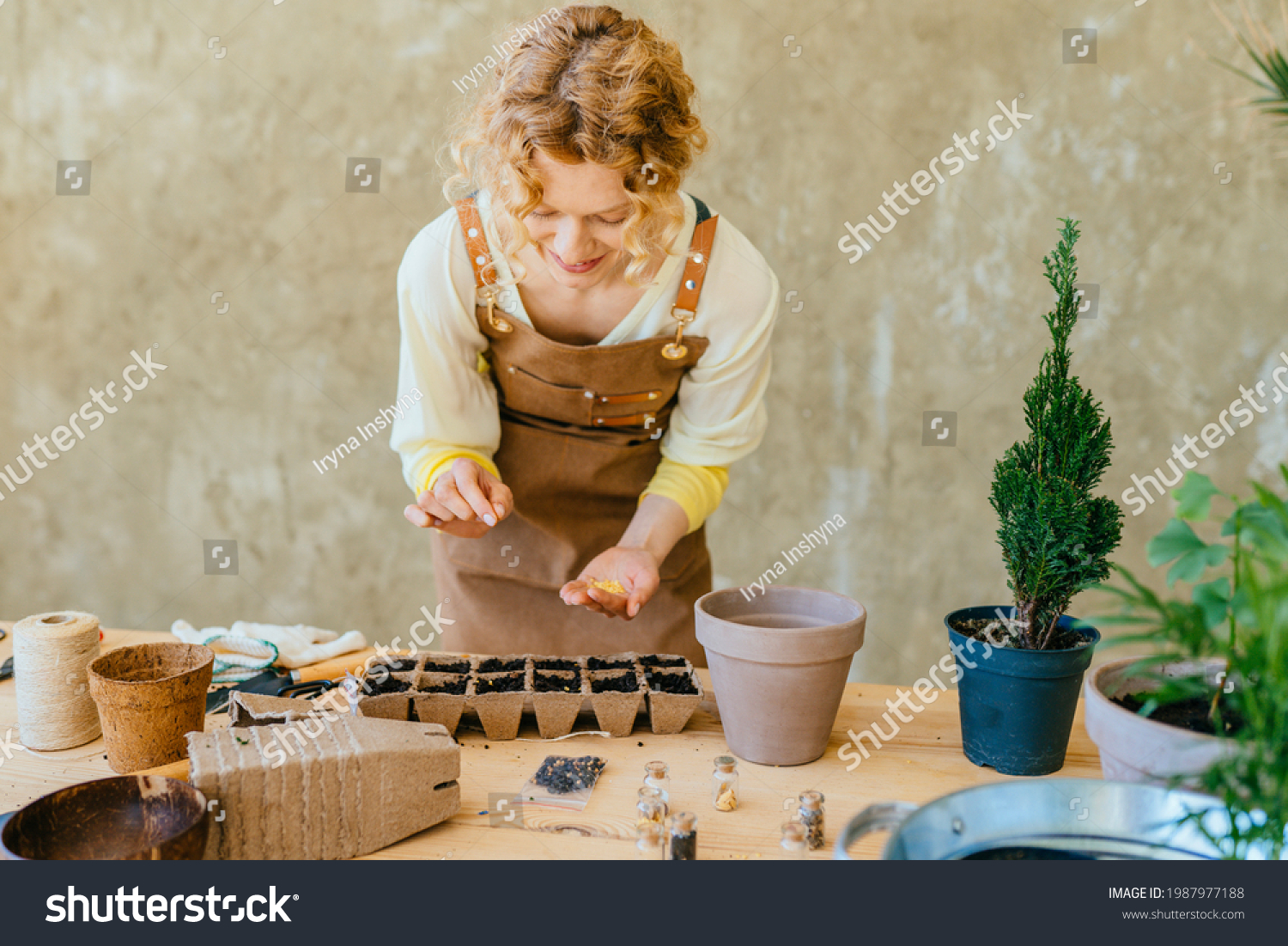 Portrait of happy female gardener working in home garden holds seeds in ...