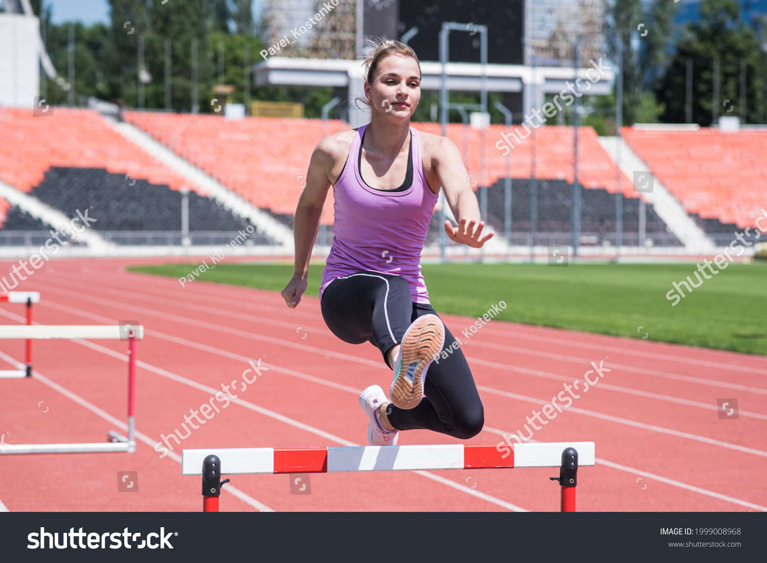 Woman athlete jumping over an obstacle. Running with hurdles. Active ...