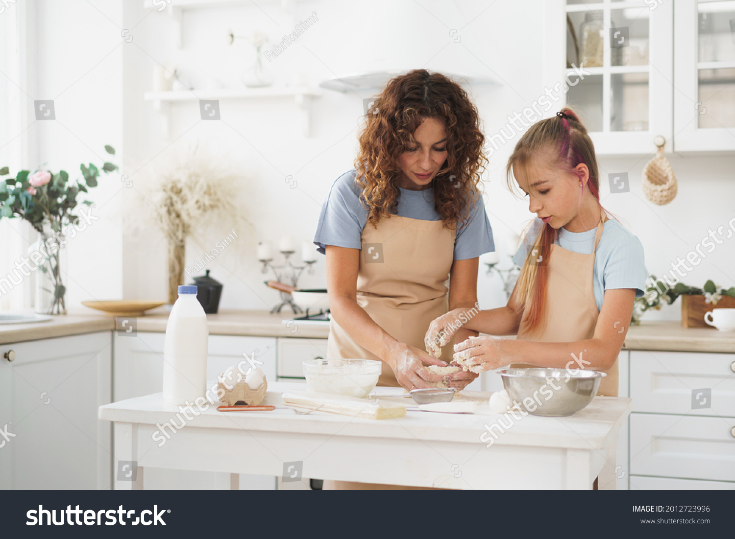 Teen girl helping her mom to cook dough in their kitchen at home_站酷海洛 ...