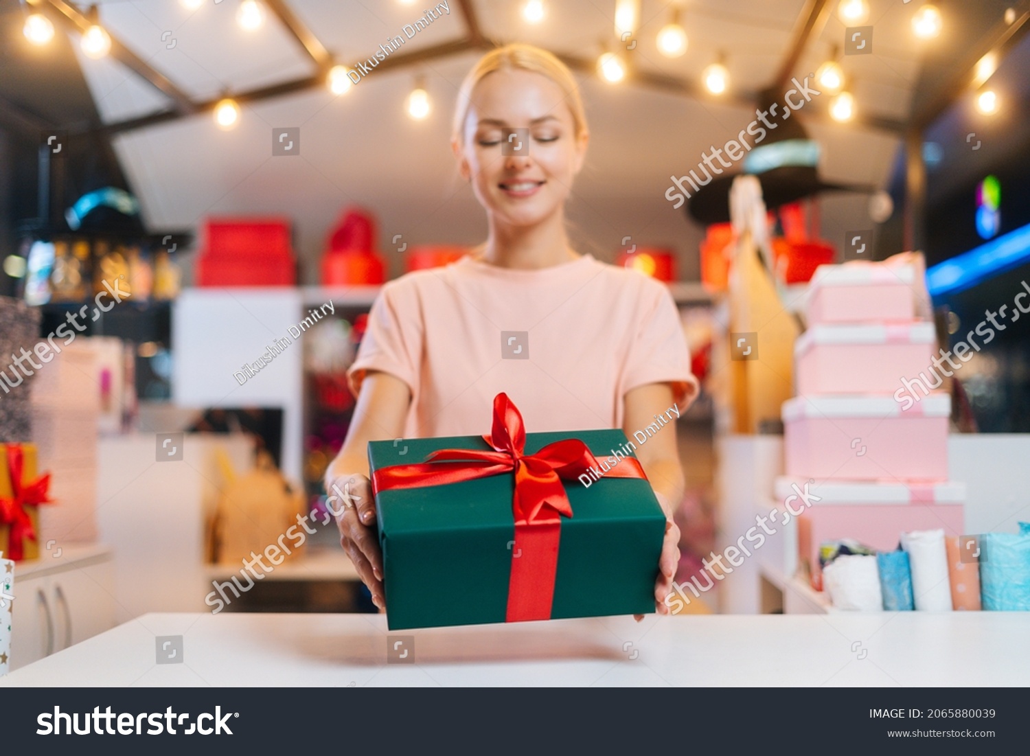 Focus on foreground of young sales woman offering take Christmas gift ...