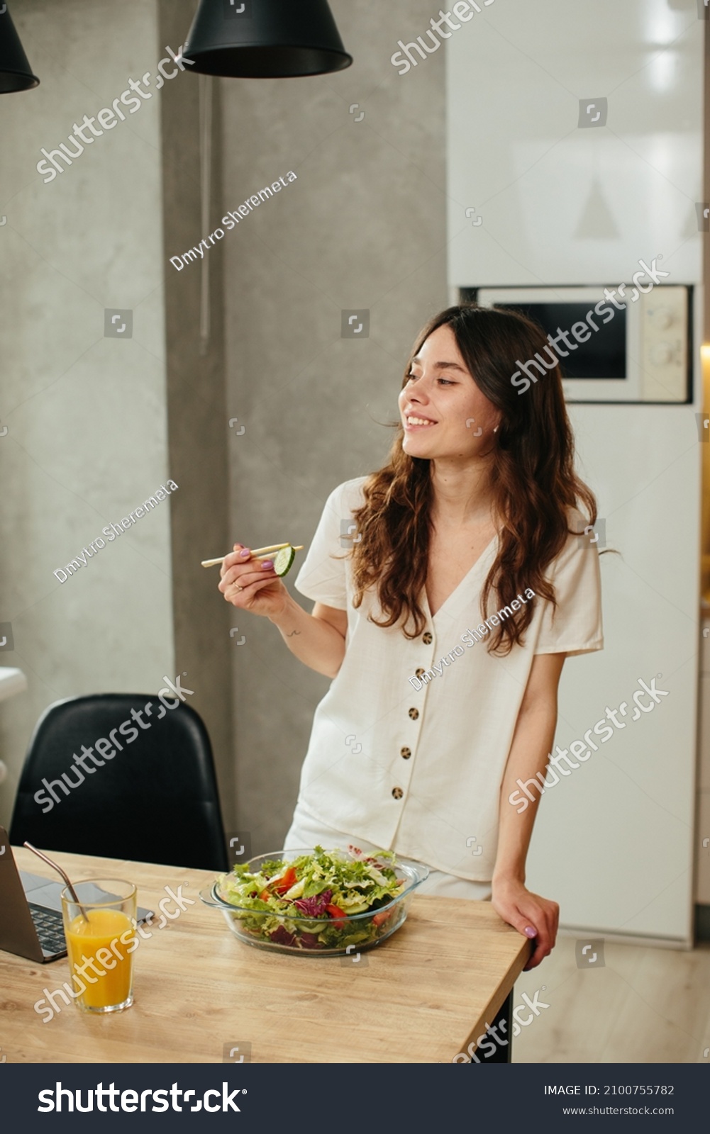 Young woman eating salad while sitting in kitchen - stock photo_站酷海洛_正版图片_视频_字体_音乐素材交易平台_站酷旗下品牌