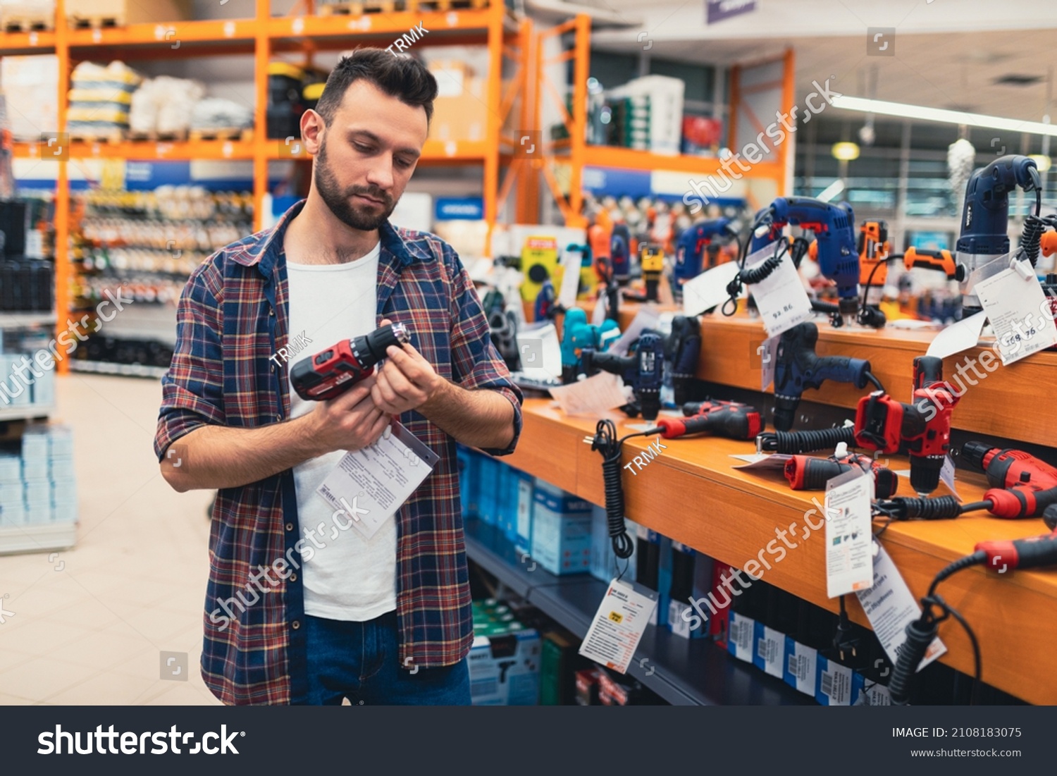 a man in a hardware store chooses a new screwdriver next to a showcase ...