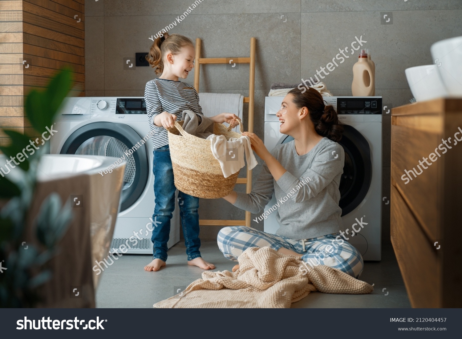 Beautiful young woman and child girl little helper are having fun and smiling while doing ...