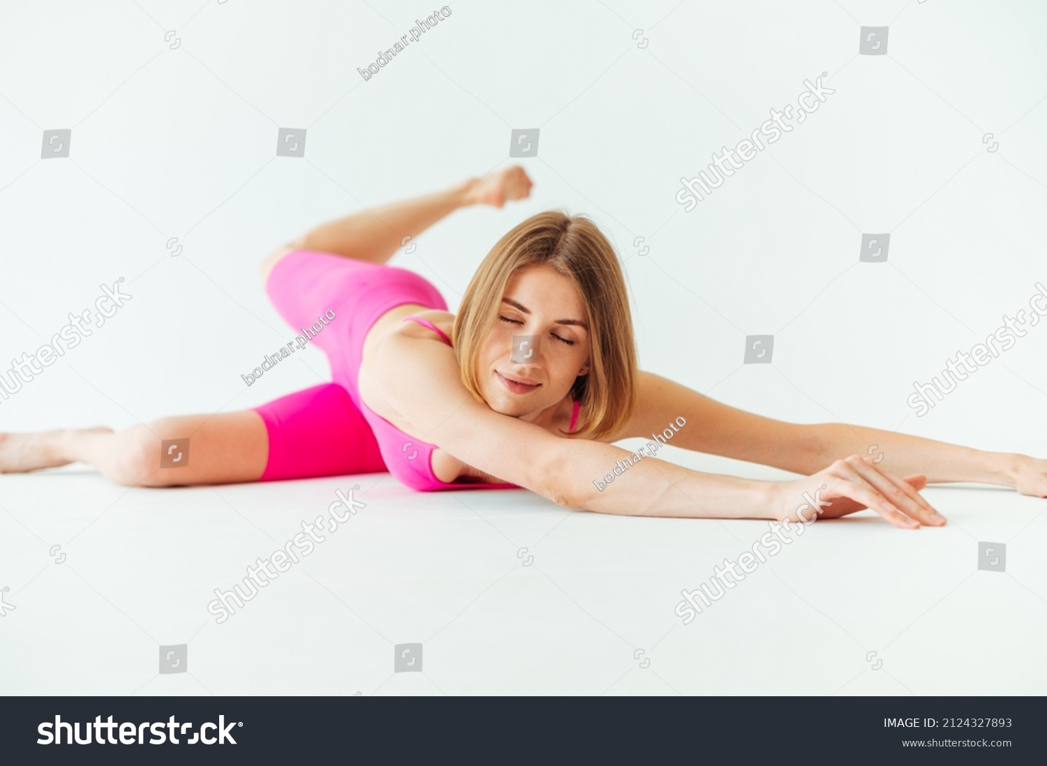Positive lady is stretching on a white background lying with a smile on his face and eyes closed ...