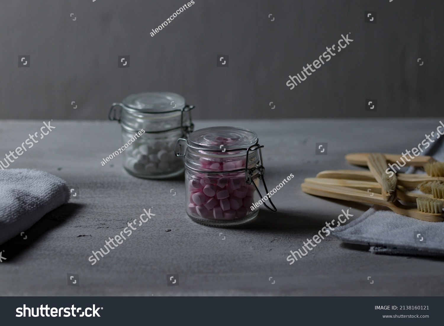 Pink and white vegan toothpastes in clear glass containers and ...