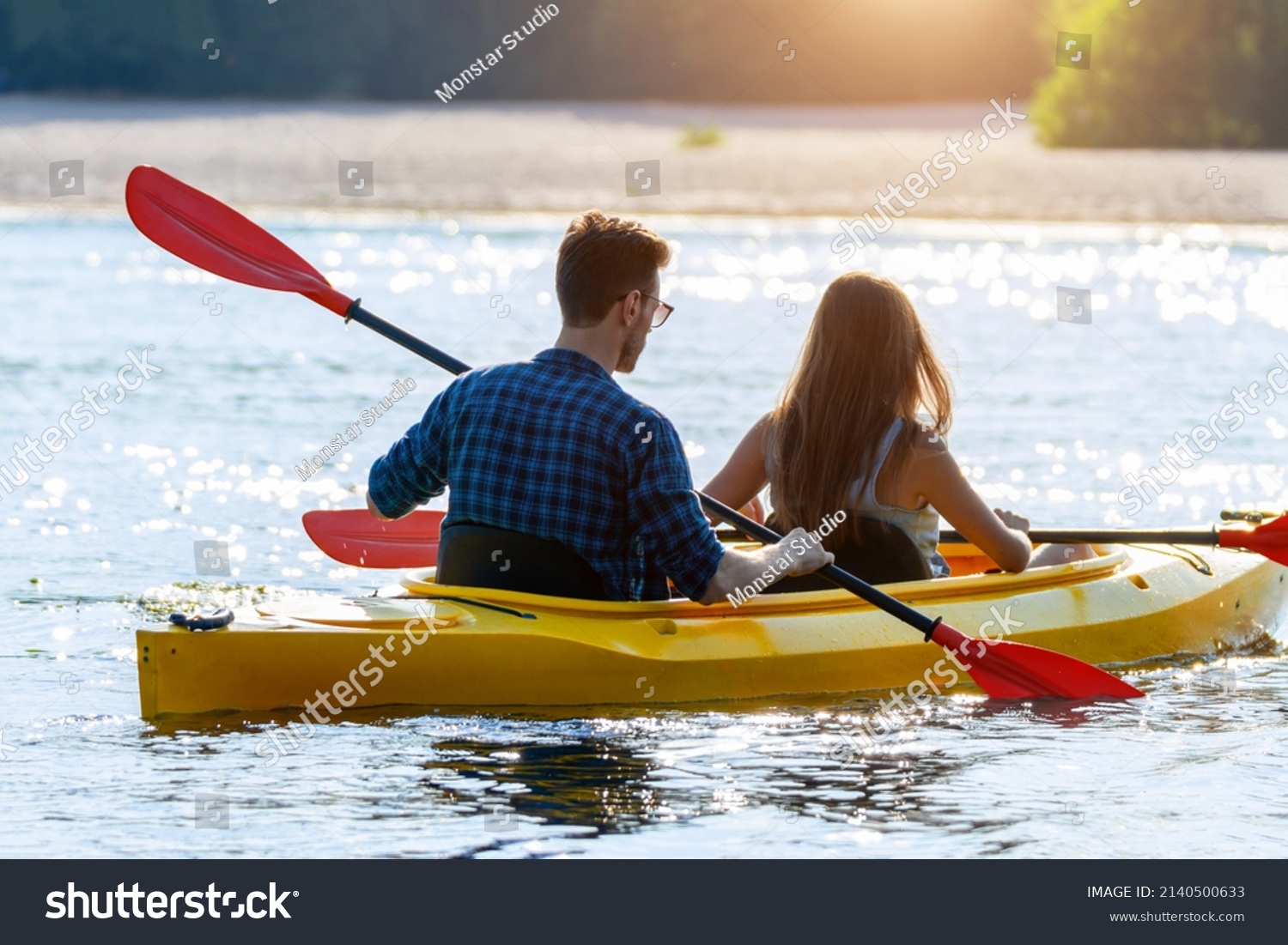 Confident young caucasian couple kayaking on river together with sunset ...