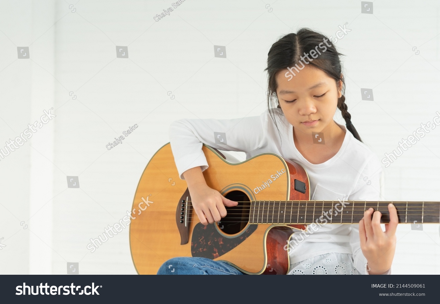 beautiful young children show playing guitar look below copy space at left. asian children study ...