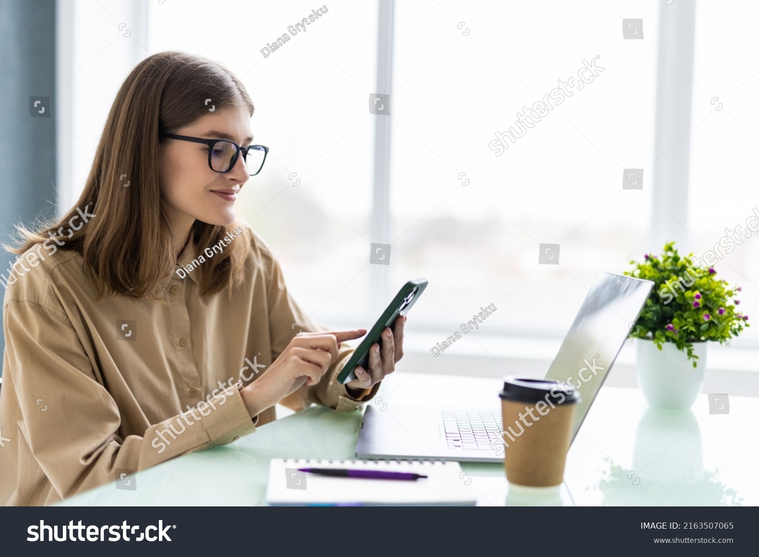 young woman working from home using smart phone and computer woman's ...
