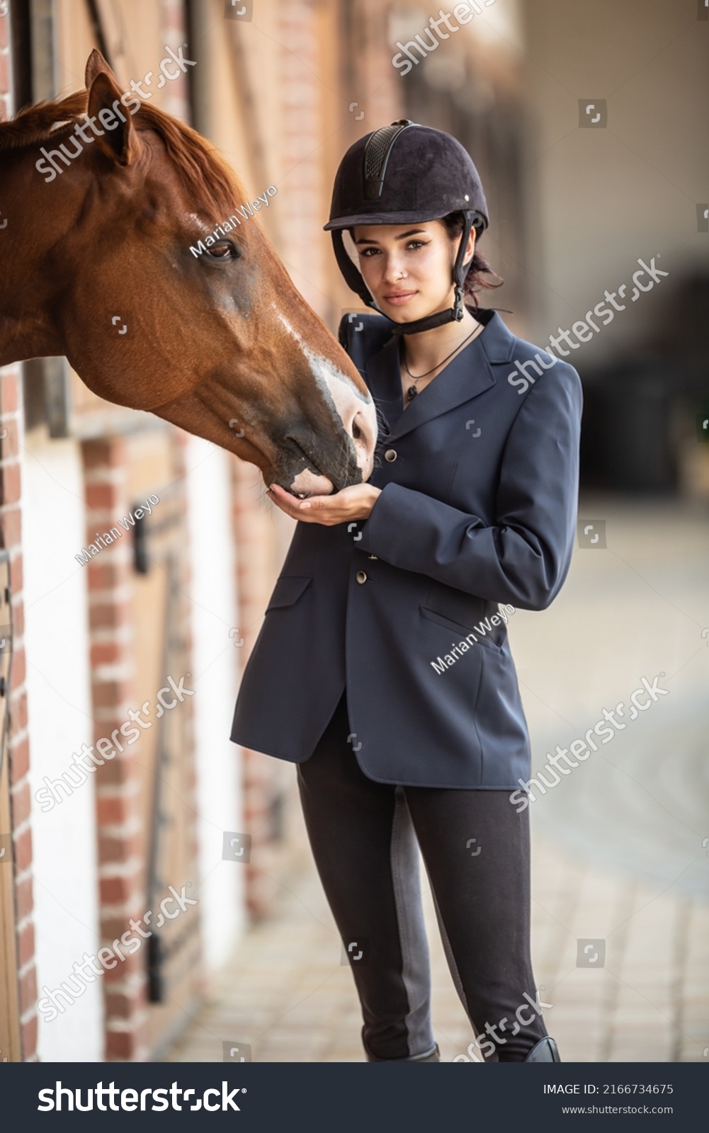 Beautiful young female jockey stands dressed up for the race next to its stabled paint horse._站酷 ...